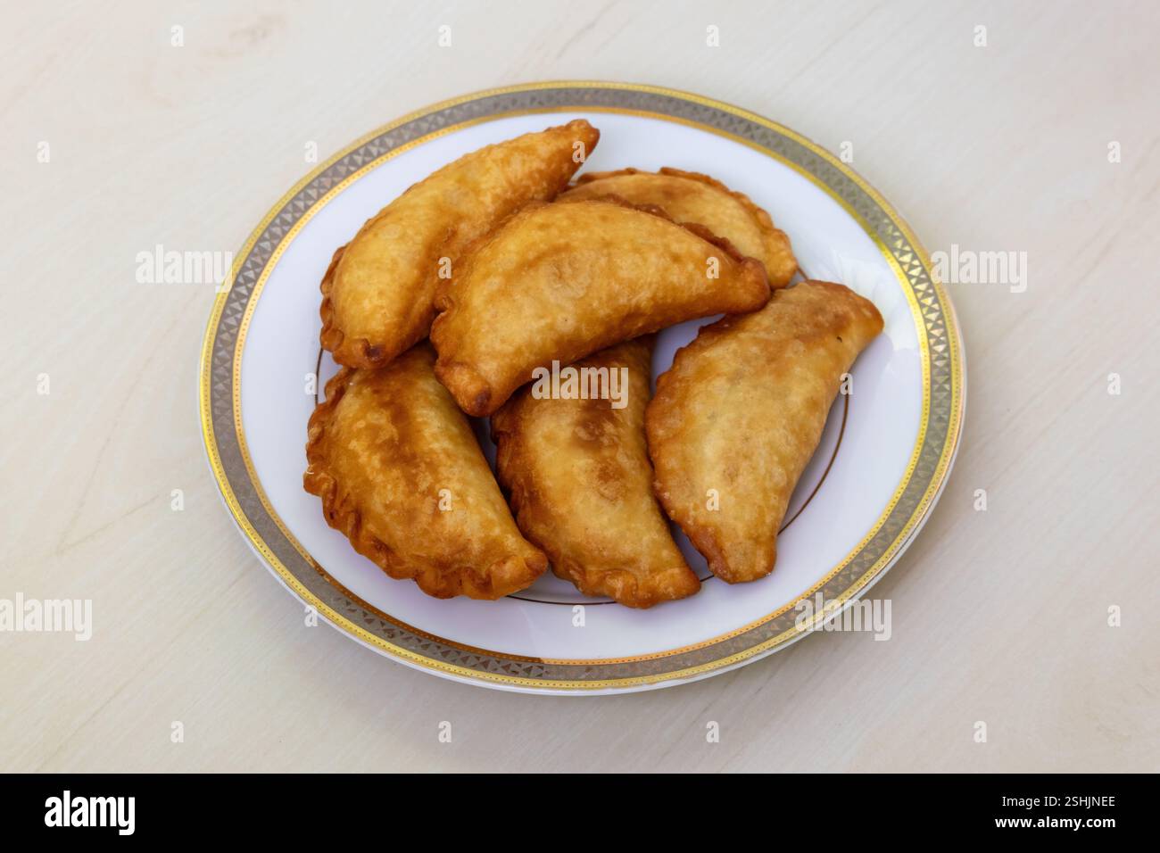 Tasty Chicken Puli Pitha, fried and served on a white plate on a wooden ...
