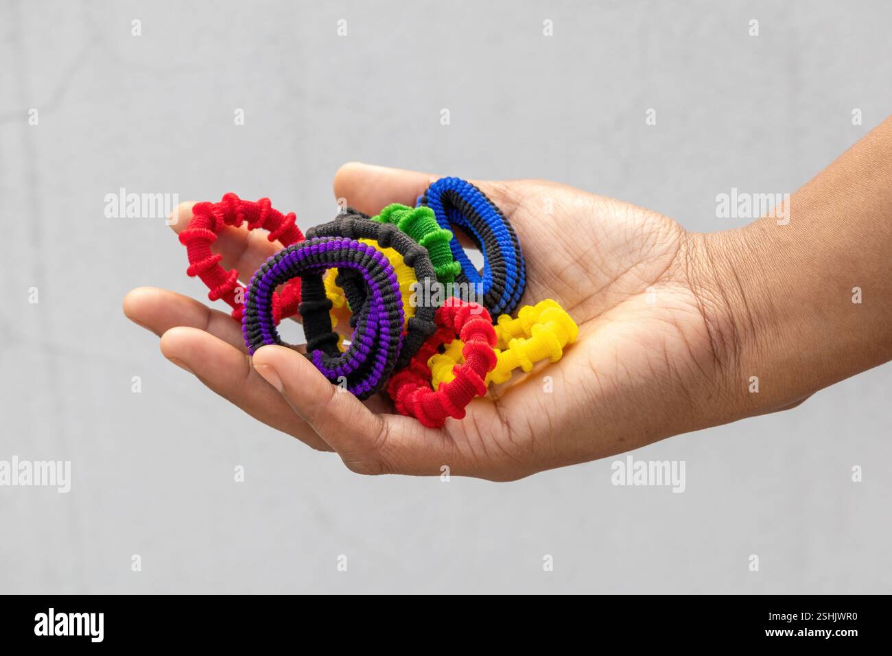 A female hand holding a collection of colorful scrunchies. These are ...