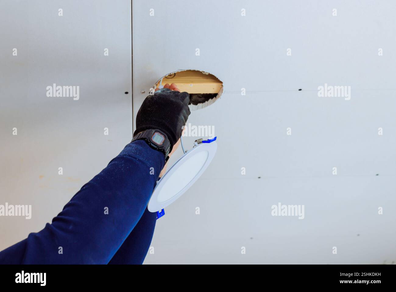 Contractor works on repairing ceiling led light by fixing cut out ...