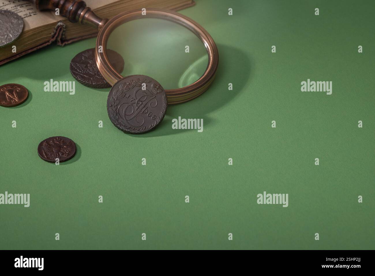 Numismatics. Ancient collectible coins and magnifying glass on a green ...