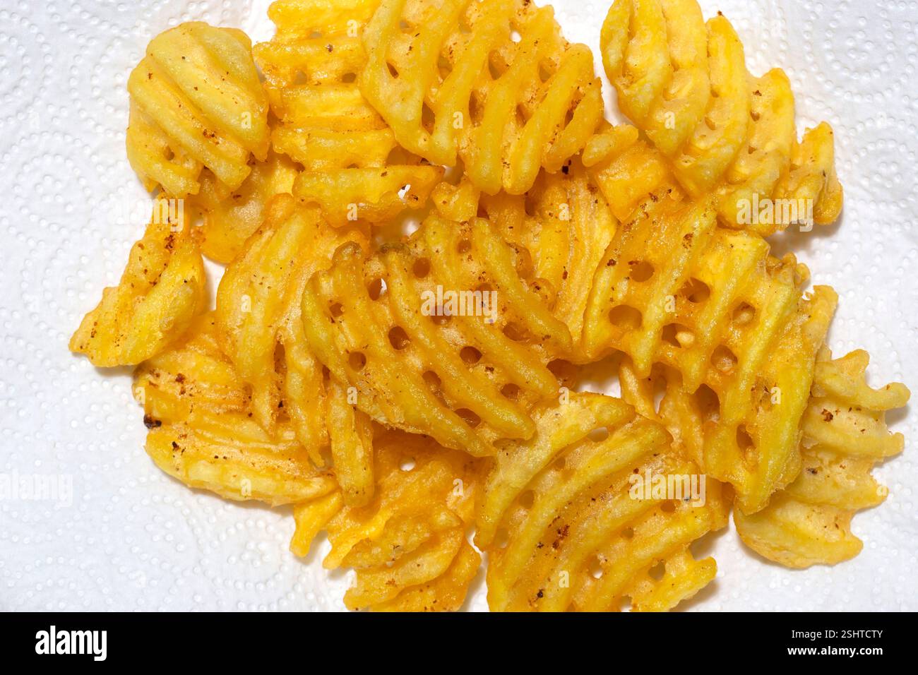 waffle criss cross fries, freshly fried, on kitchen paper towel ...