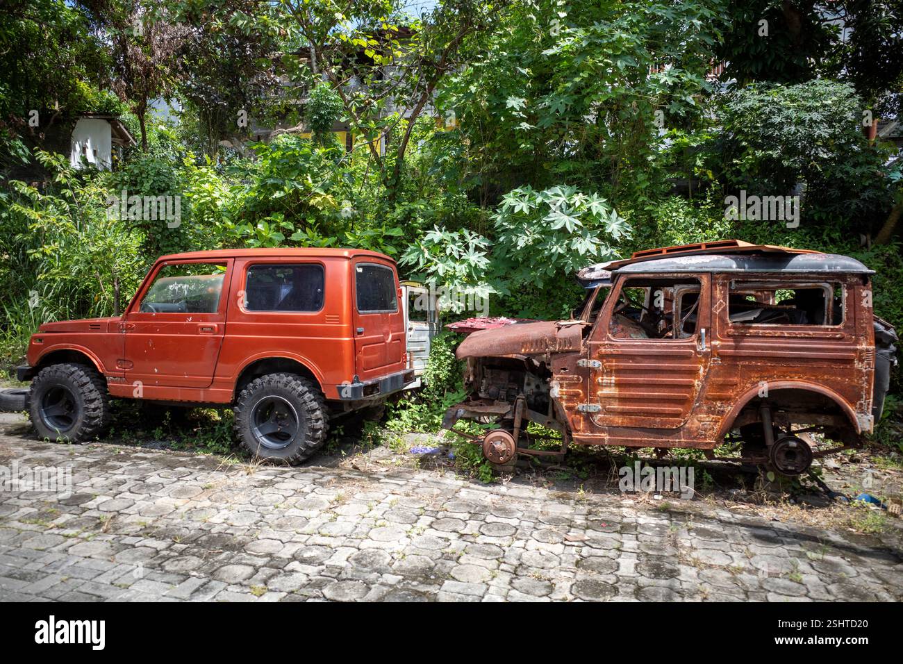 An old red car and a rusty older generation car without wheels Stock Photo - Alamy