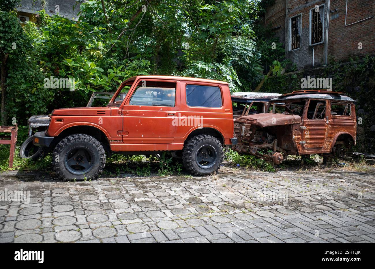 An old red car and a rusty older generation car without wheels Stock ...