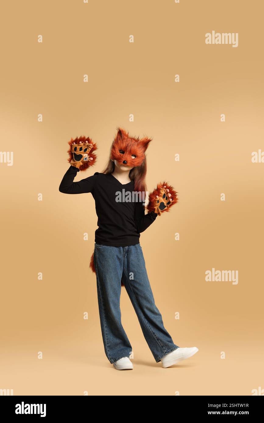 Quadrobics. Girl wearing fox mask, tail and gloves on beige background ...