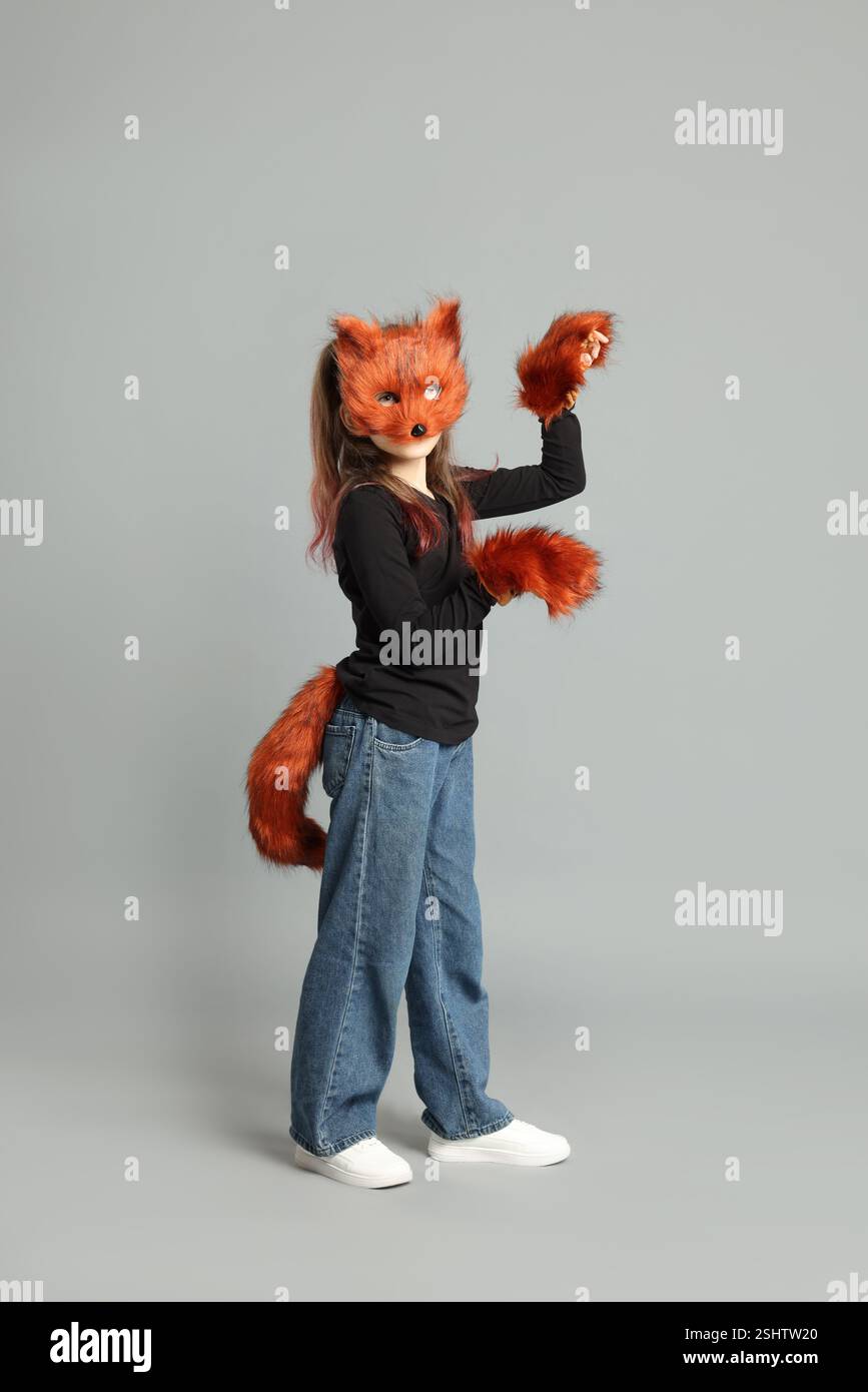 Quadrobics. Girl wearing fox mask, tail and gloves on grey background ...