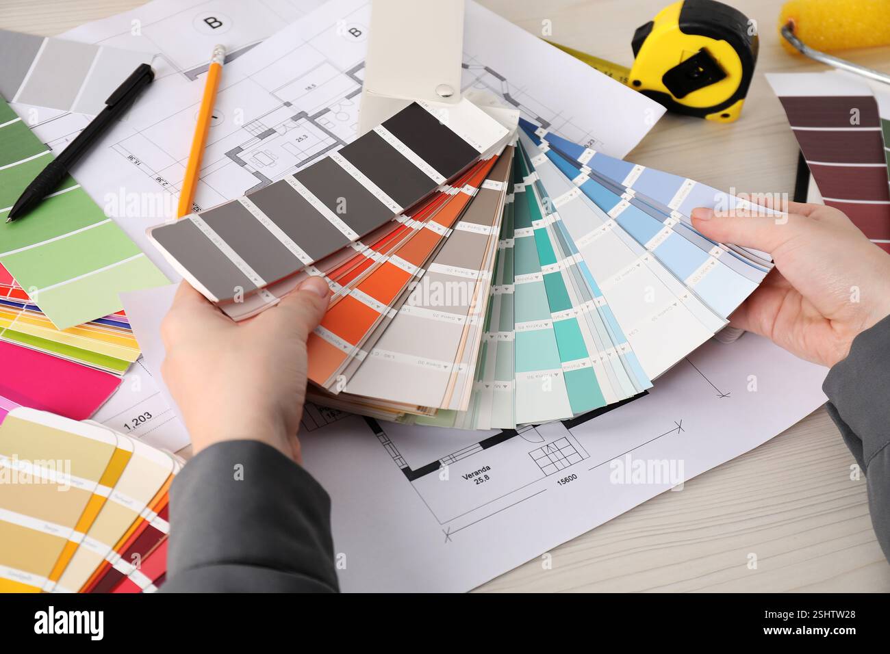 Designer with color selection chart working at white wooden table ...