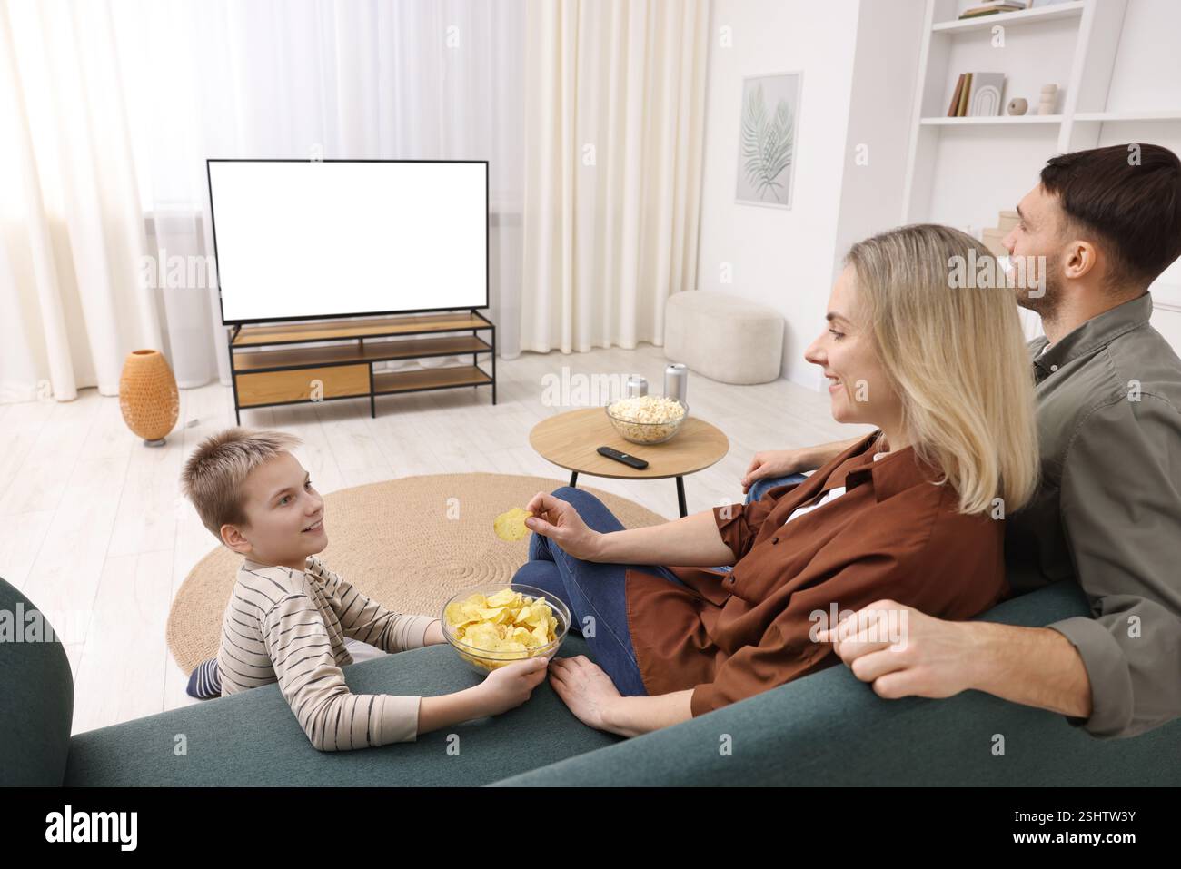 Happy family with snacks and drinks watching tv together at home Stock ...