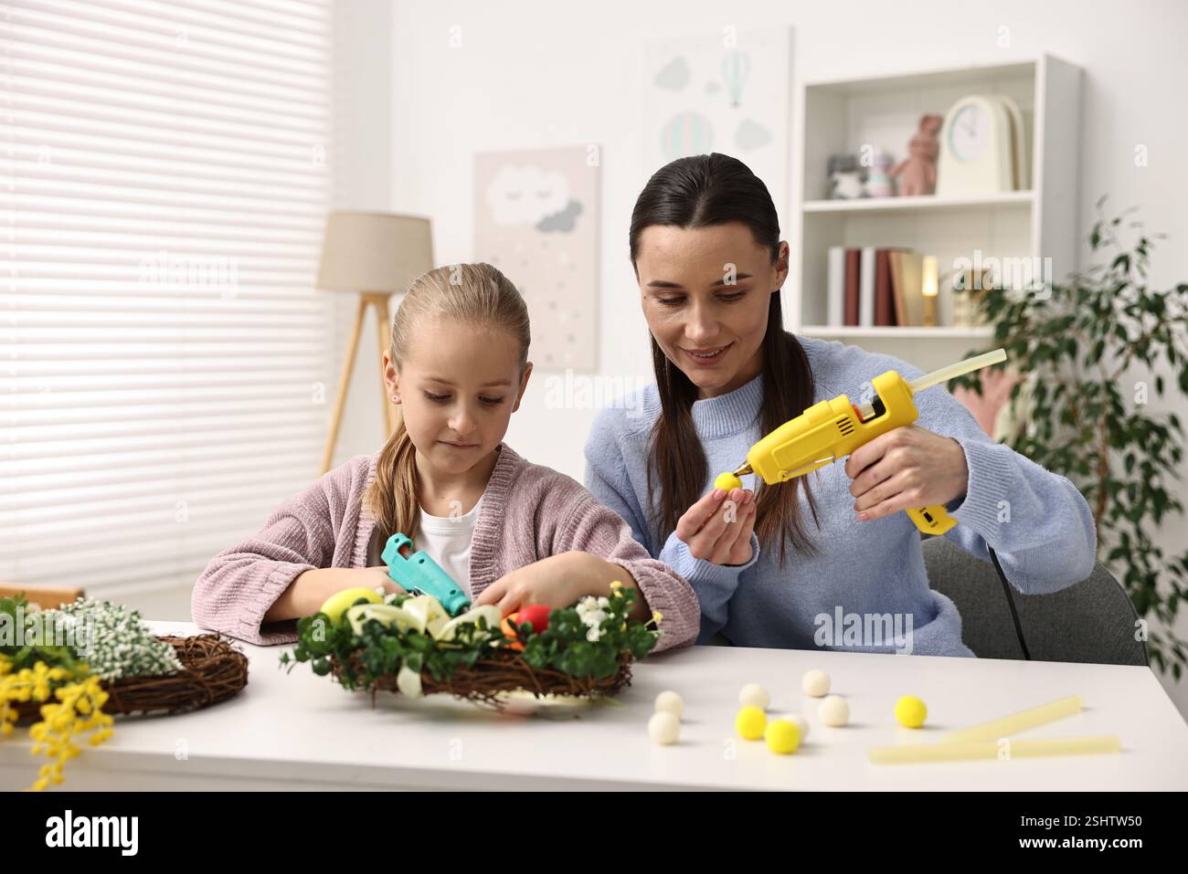 Mother and daughter with hot glue guns creating Easter composition at ...