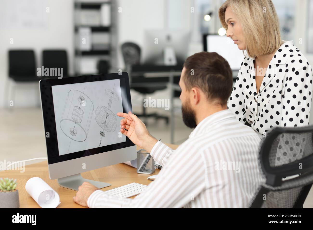 Technicians making digital engineering drawing on computer at desk in ...