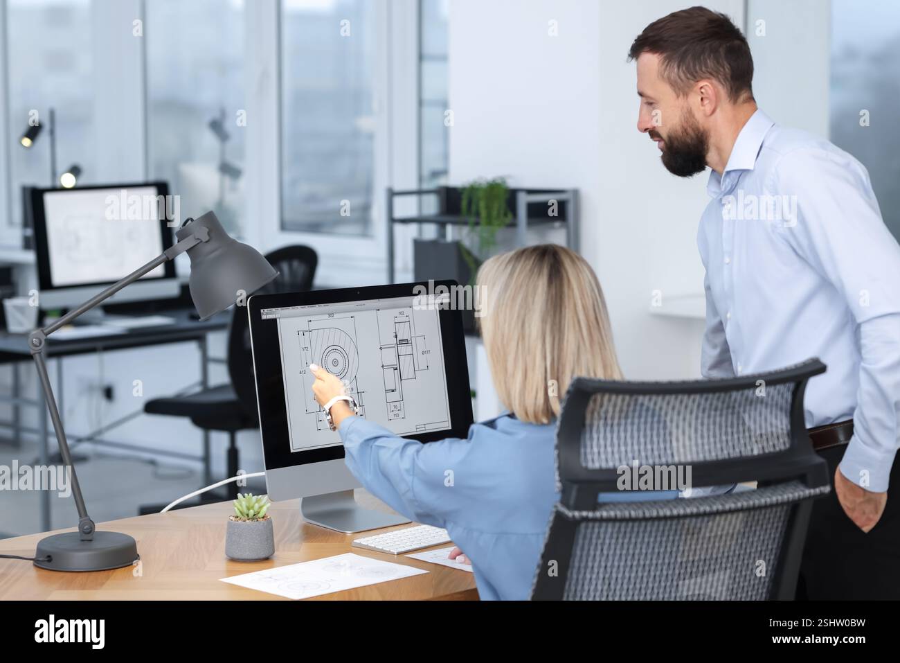 Technicians making digital engineering drawing on computer at desk in ...
