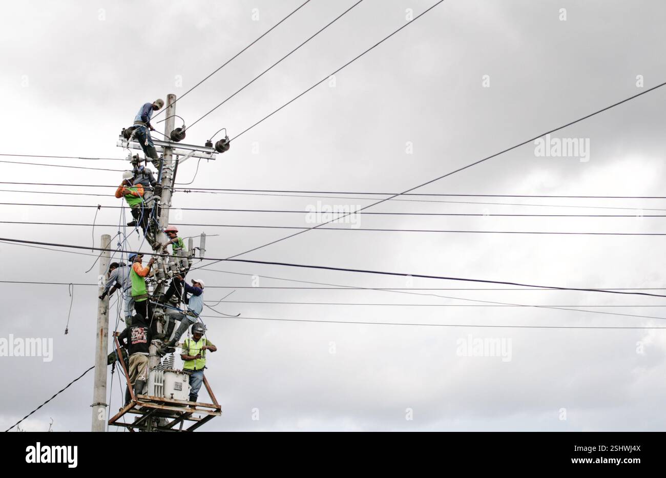 Workers engaged in electrical maintenance on power lines in Indonesia ...
