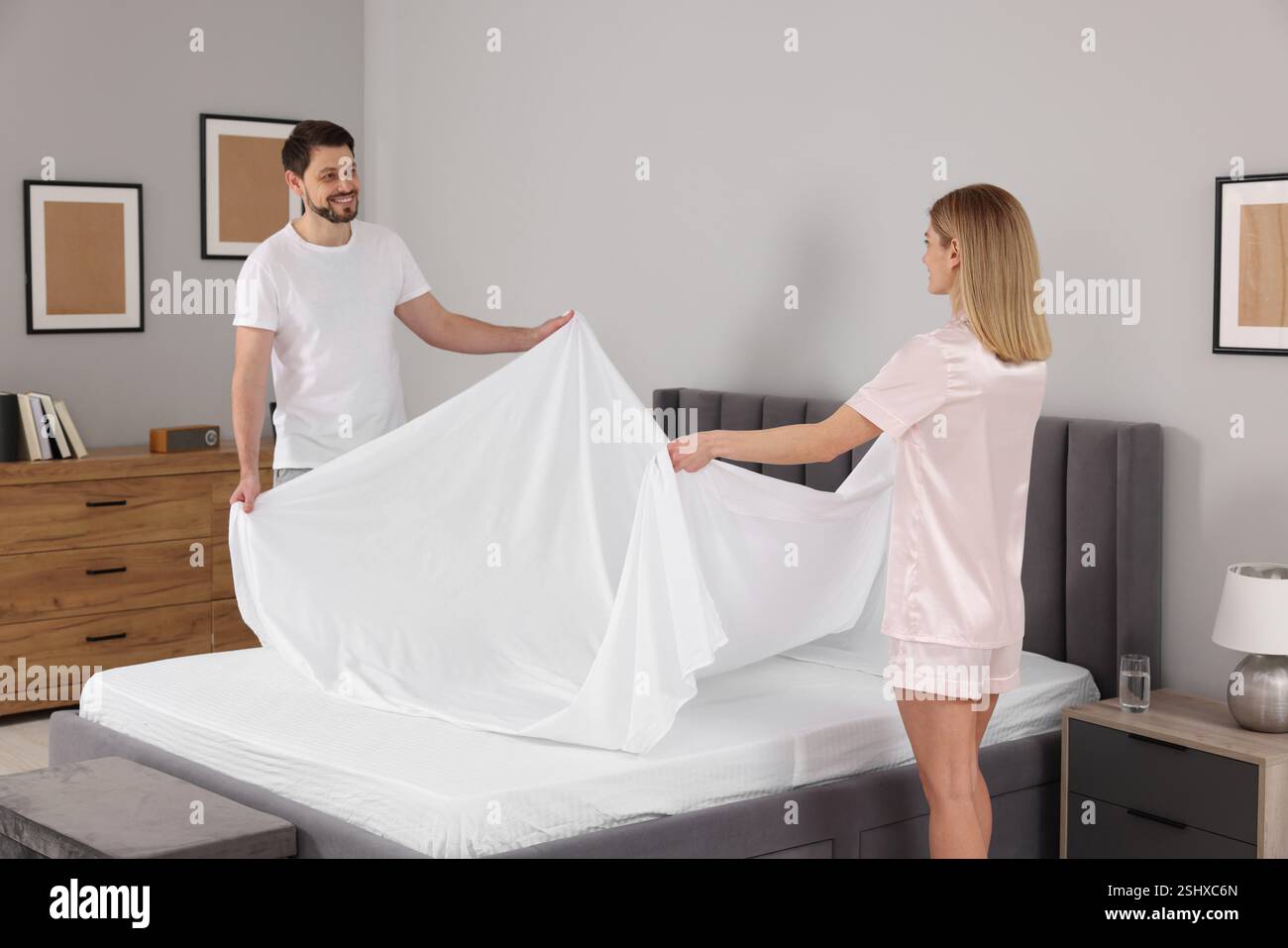Couple changing bed linens in room. Domestic chores Stock Photo - Alamy