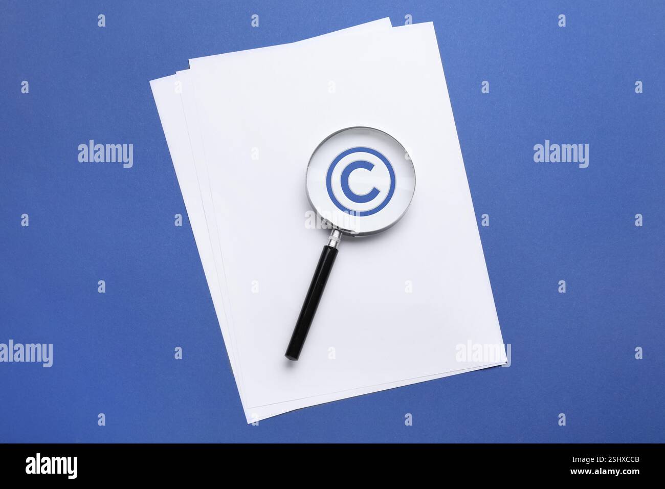 License. Paper with copyright symbol and magnifying glass on blue ...