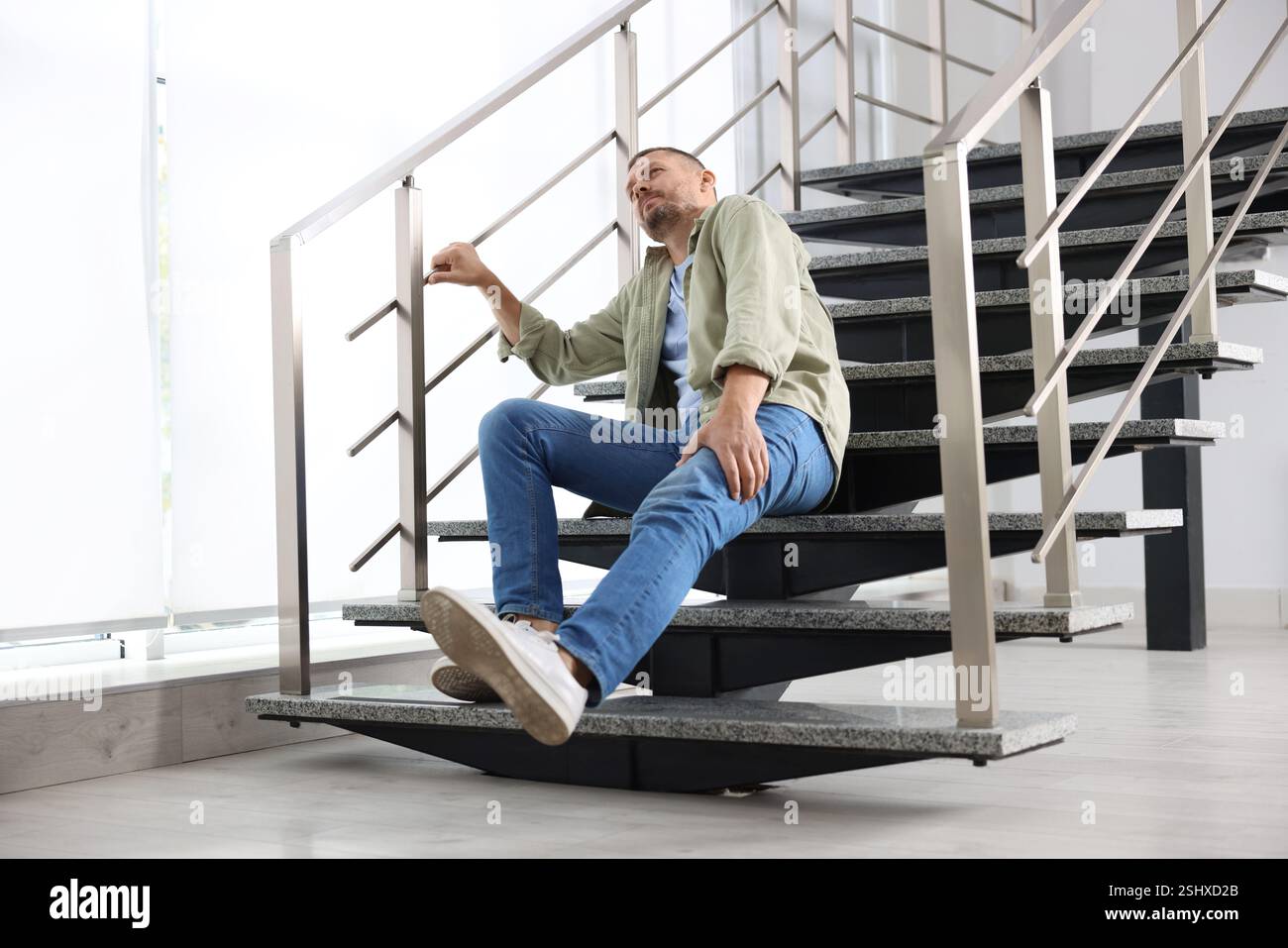 Man with injured leg on stairs in building after fall. Dangerous ...