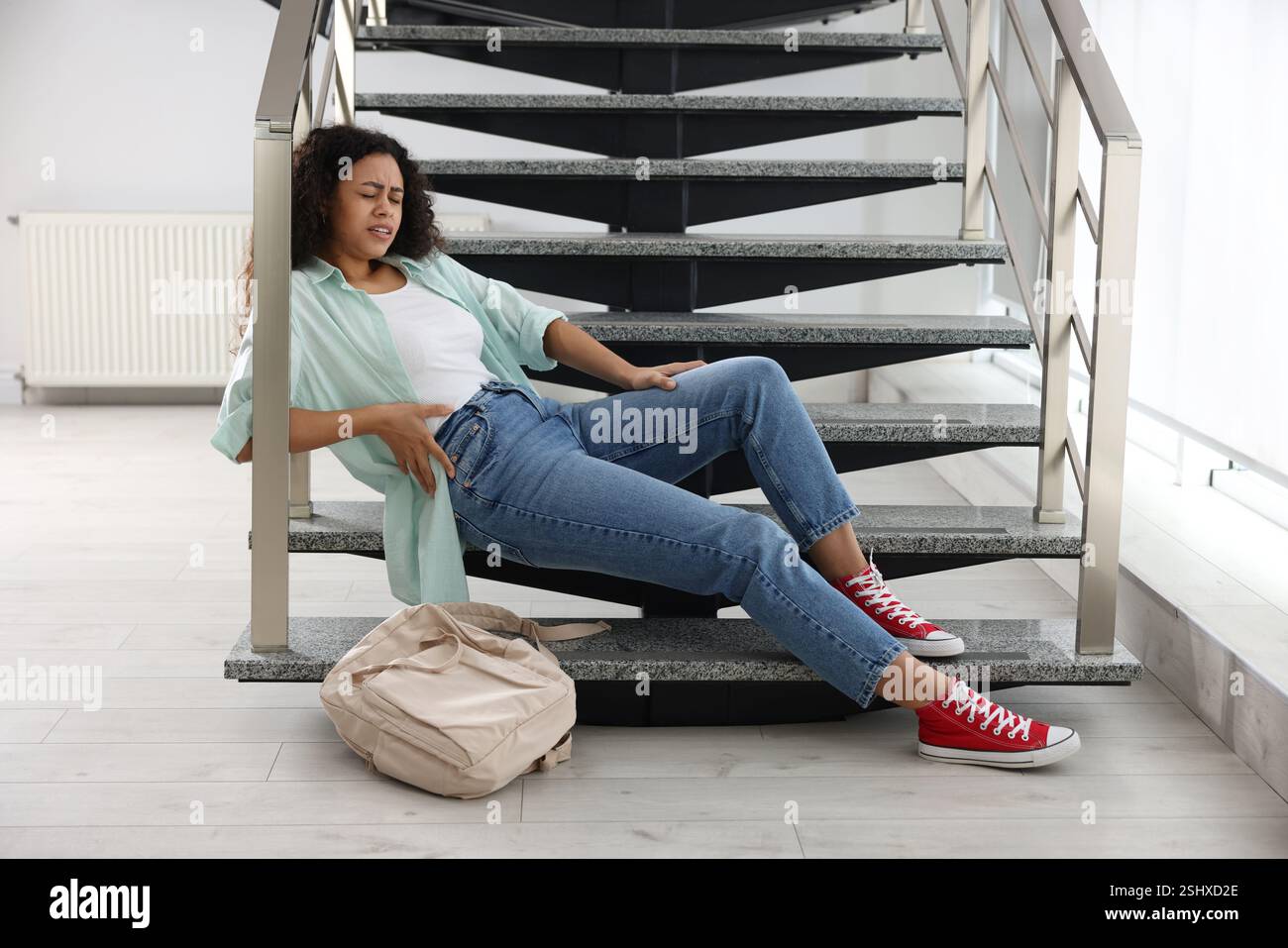 Woman with injured back on stairs in building after fall. Dangerous ...