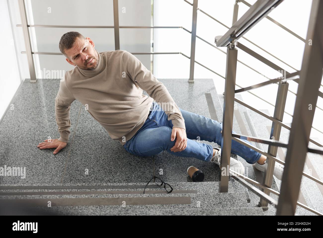 Injured man on stairs in building after fall. Dangerous accident Stock ...