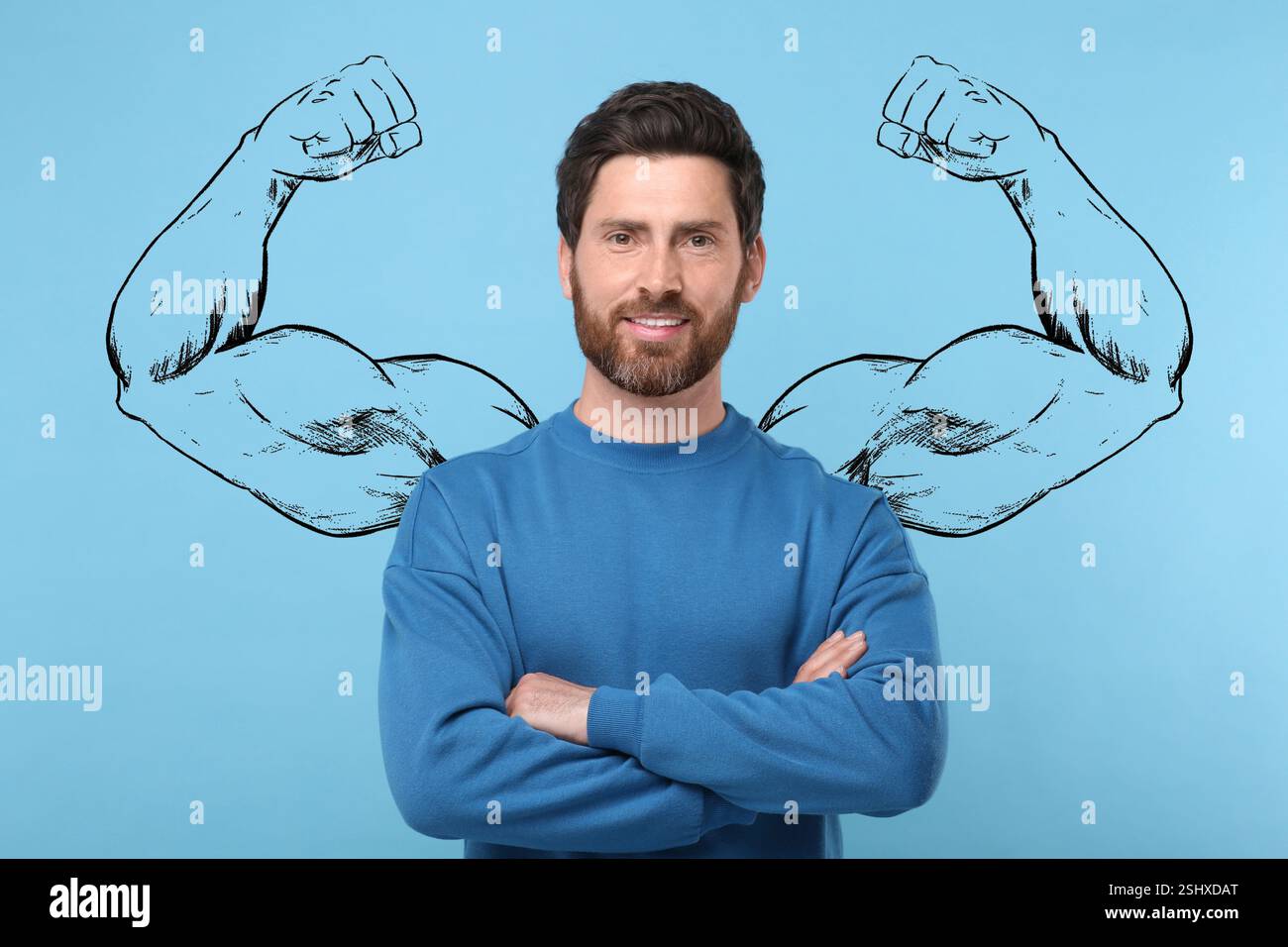 Handsome man with drawing of strong arms behind him on light blue ...