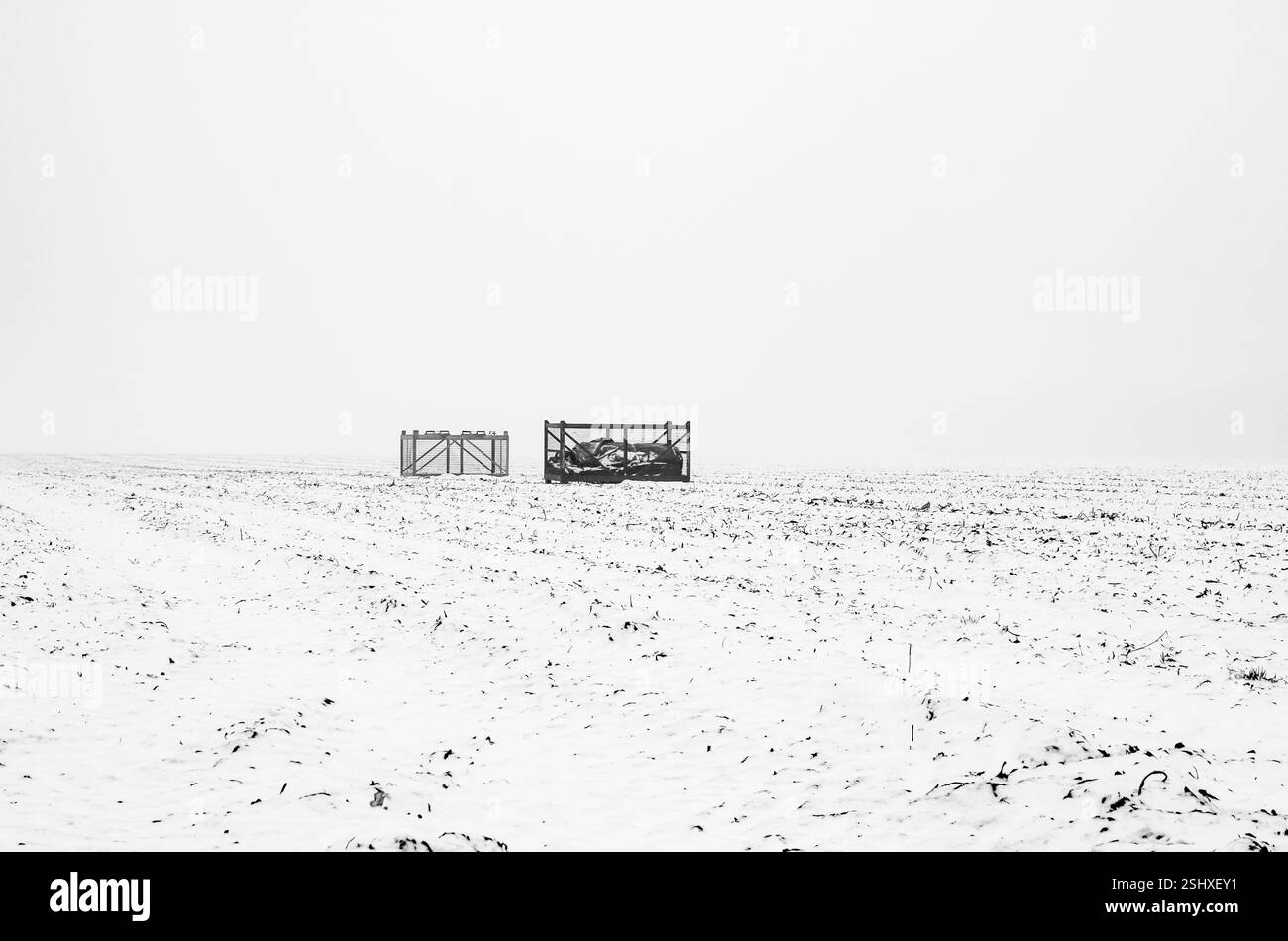 During winter two crates are staning on a with snow covered meadow ...