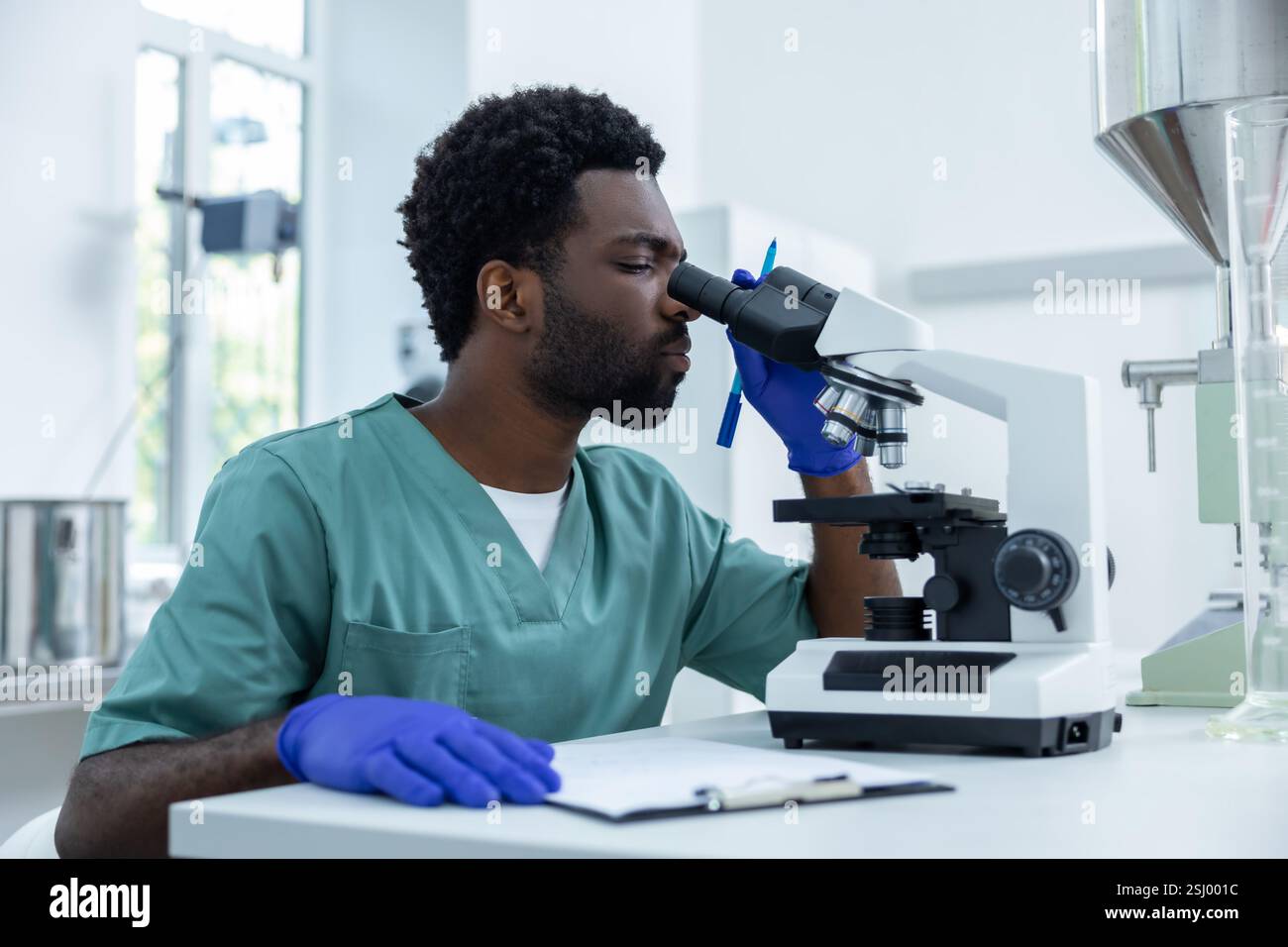 African American man scientist working with microscope laboratory conducting research Stock ...