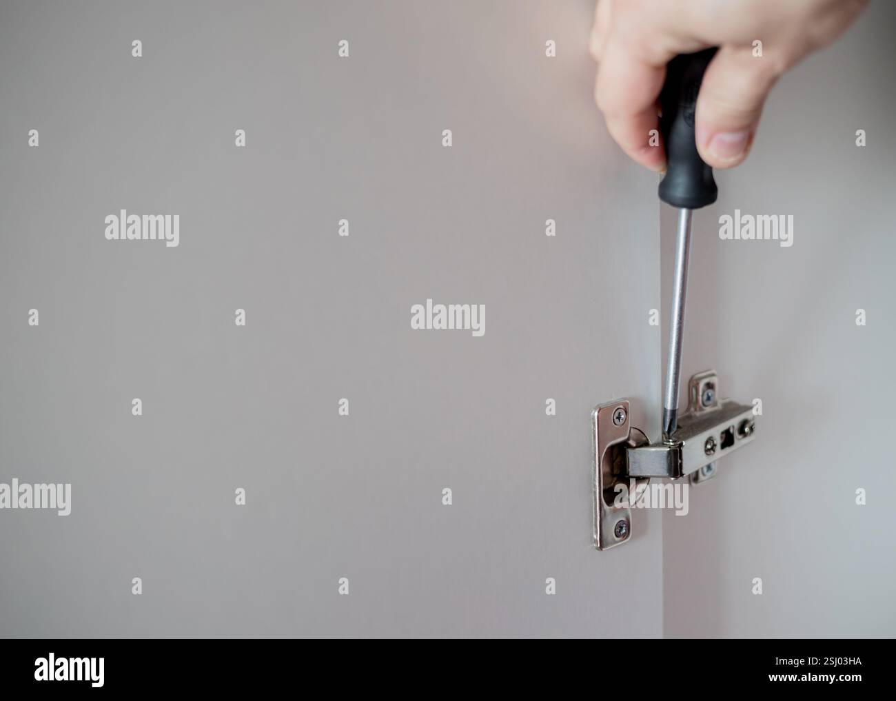 A man hands with screwdriver and screw. Assembly of a cabinet Stock ...