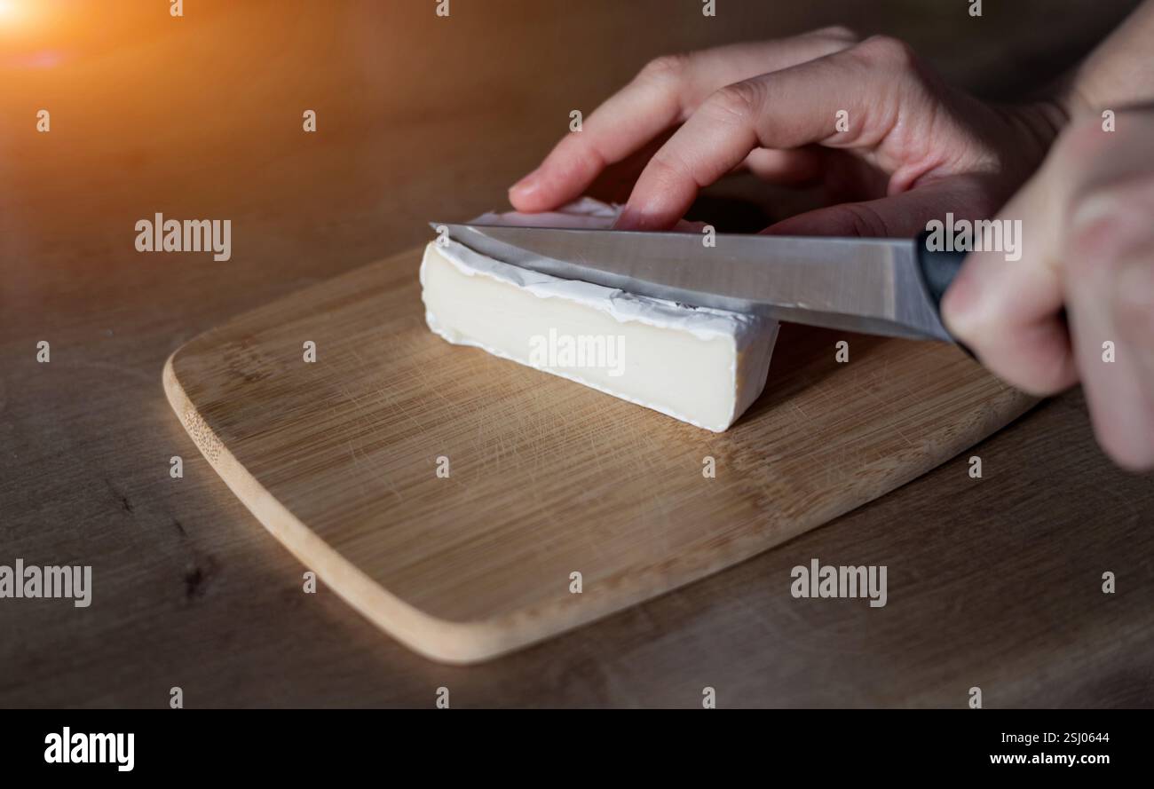 Female hands cutting of freshly unwrapped camembert cheese Stock Photo ...