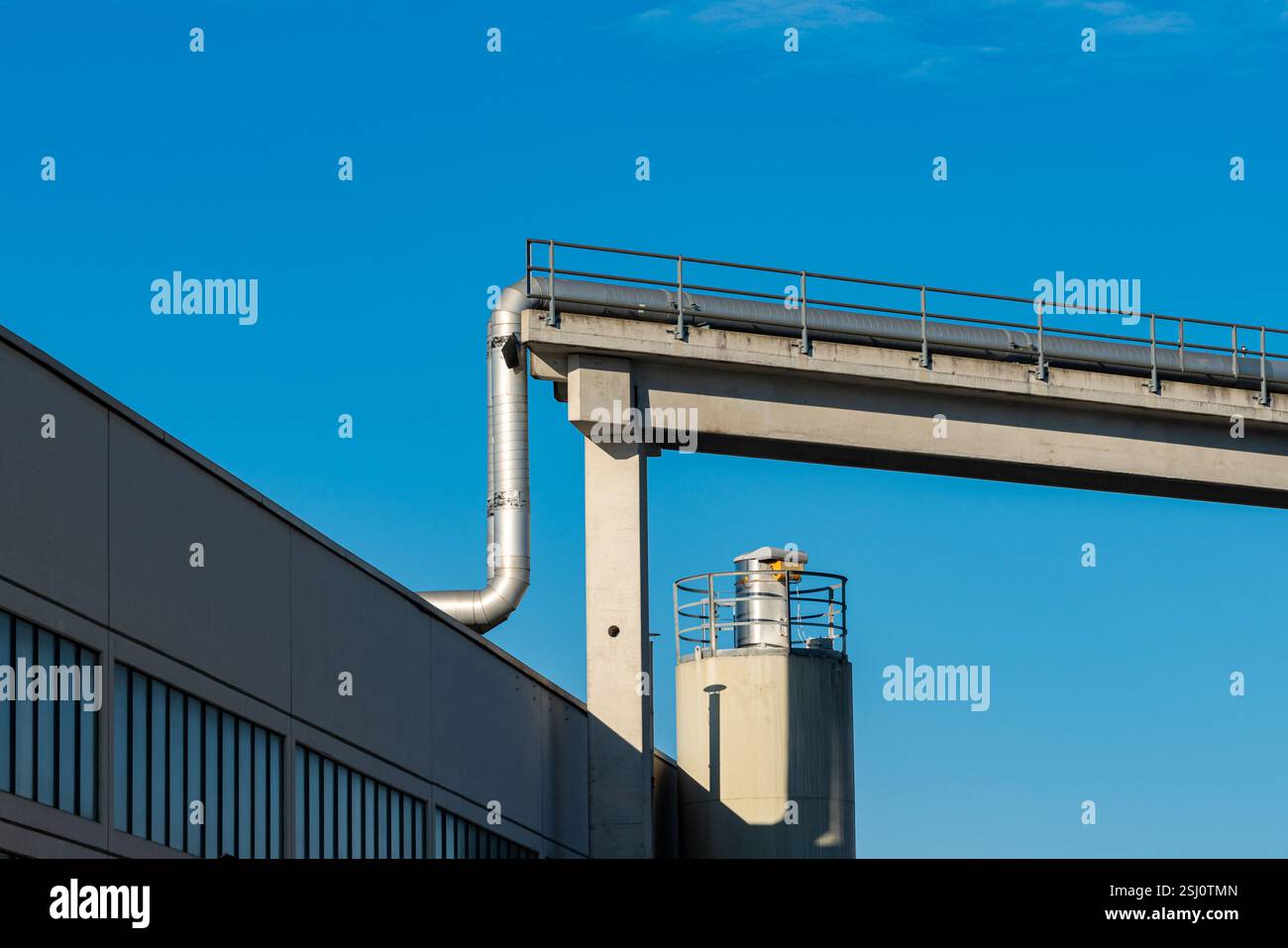 A large industrial structure features a high pipe extending above a ...