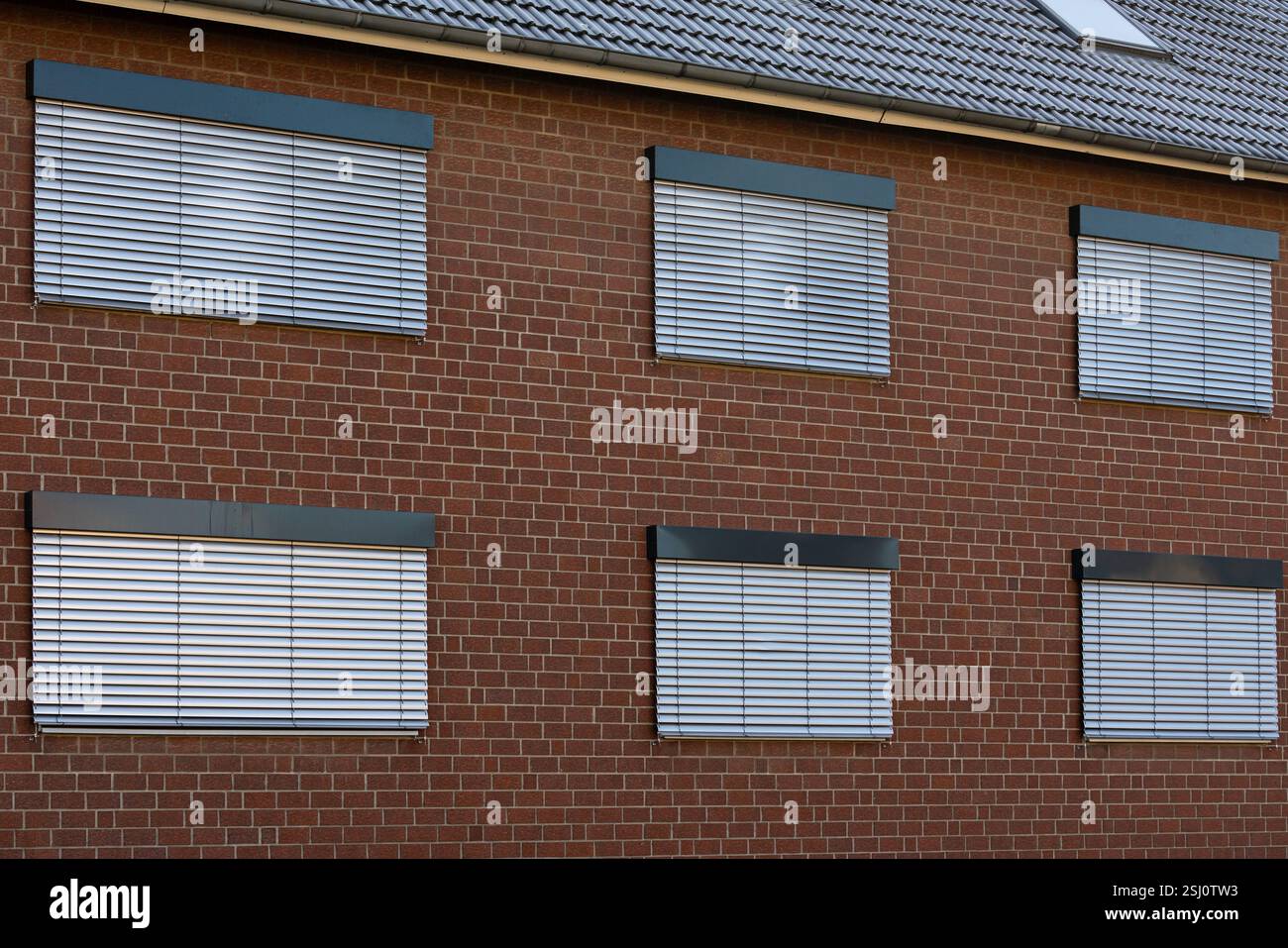 Brick walls feature multiple windows covered with horizontal blinds ...
