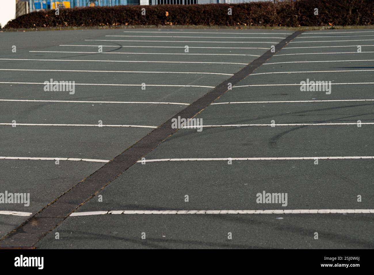 An empty parking lot features clearly marked white lines on a gray ...