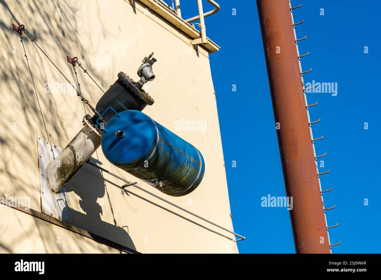 A bright blue gas tank is mounted on the exterior of a building ...