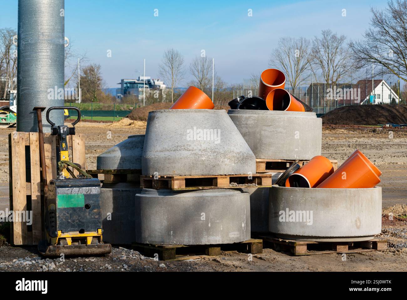 Stacks of concrete pipes rest on wooden pallets at a construction site ...