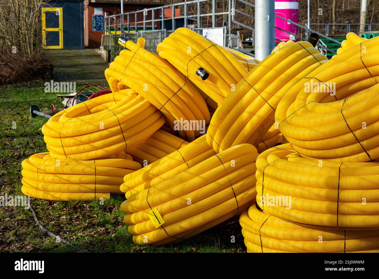 Coiled yellow hoses are stacked outdoors at a construction site during ...