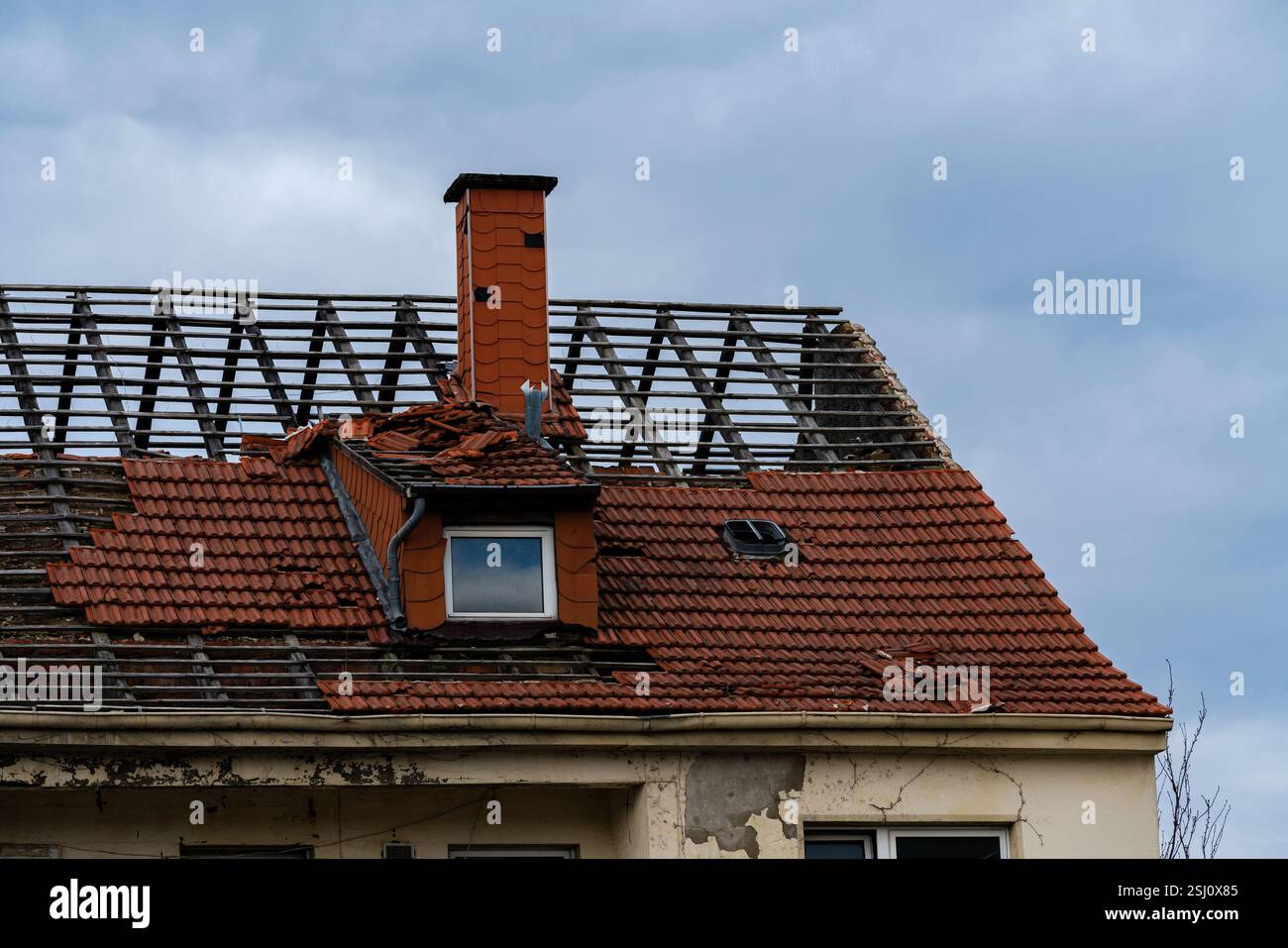 The roof shows significant damage with broken tiles and an exposed ...