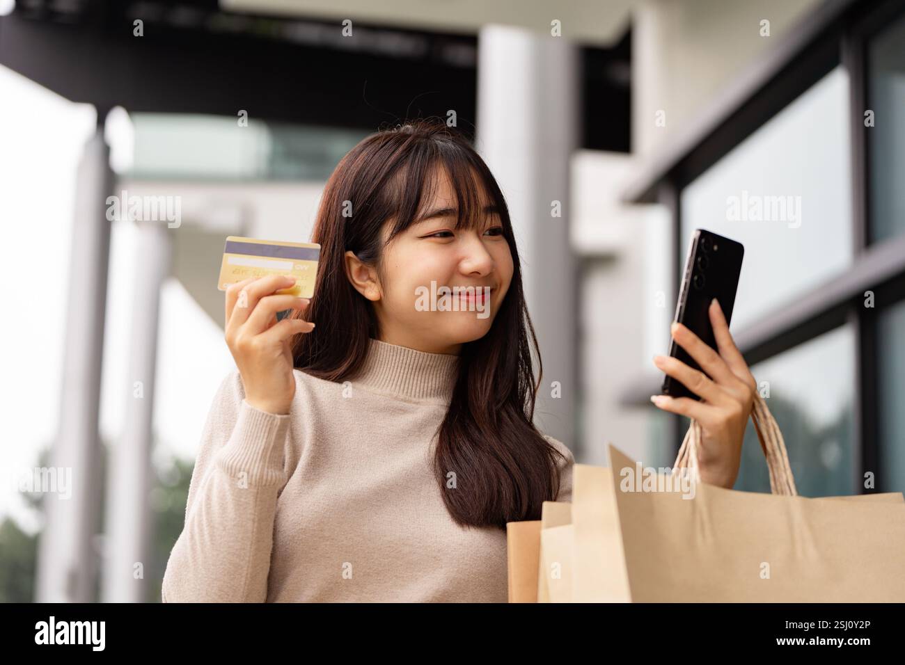 Young woman shopping with smartphone and credit card, expressing ...