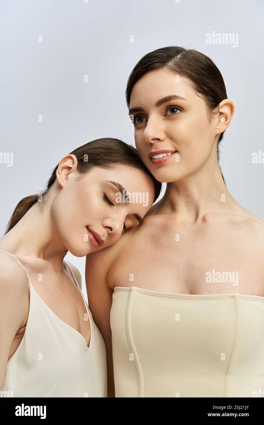 Two pretty twin sisters share a tender moment, displaying their close ...