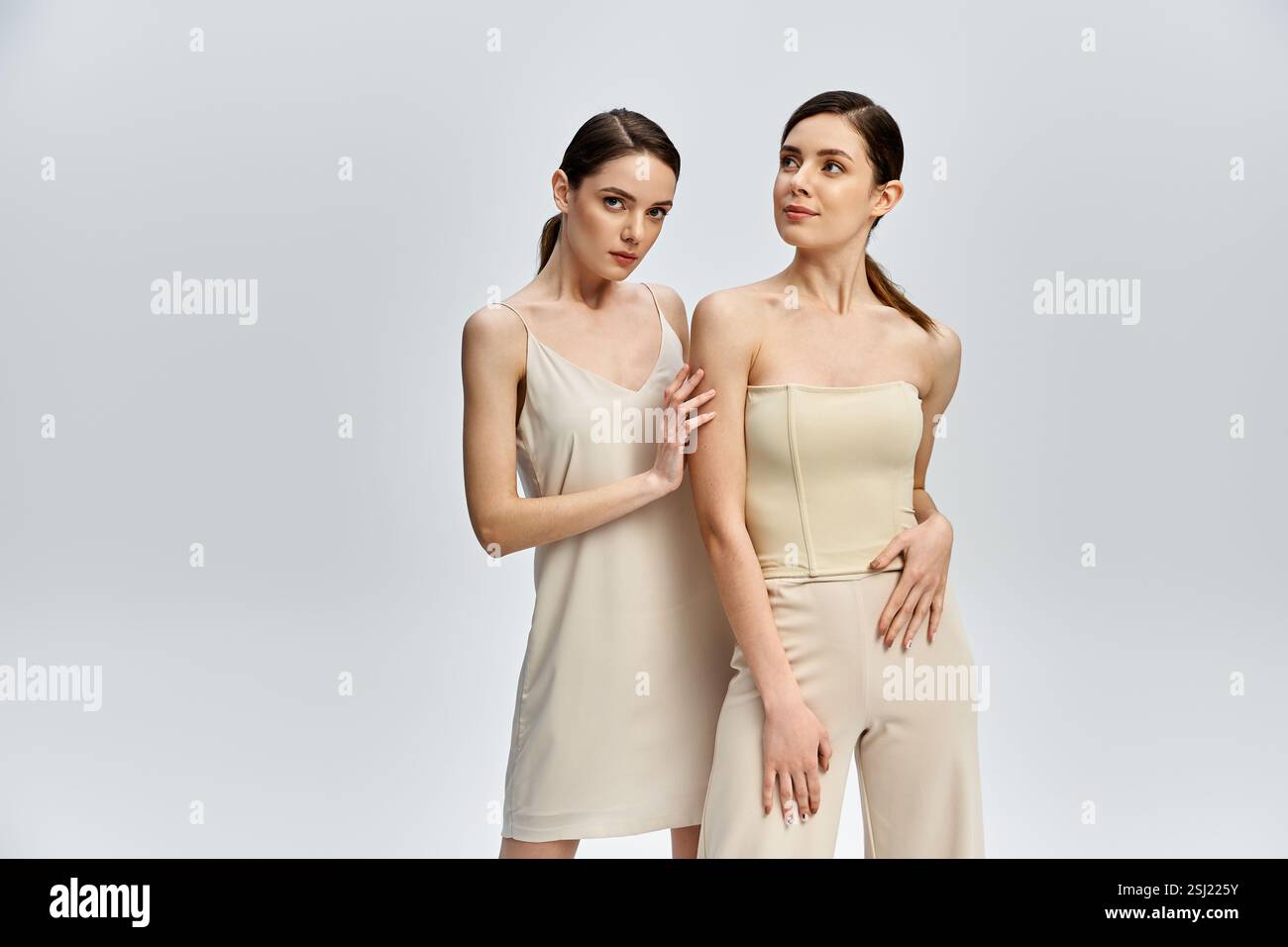 Two stunning twin sisters stand together in elegant outfits, radiating ...