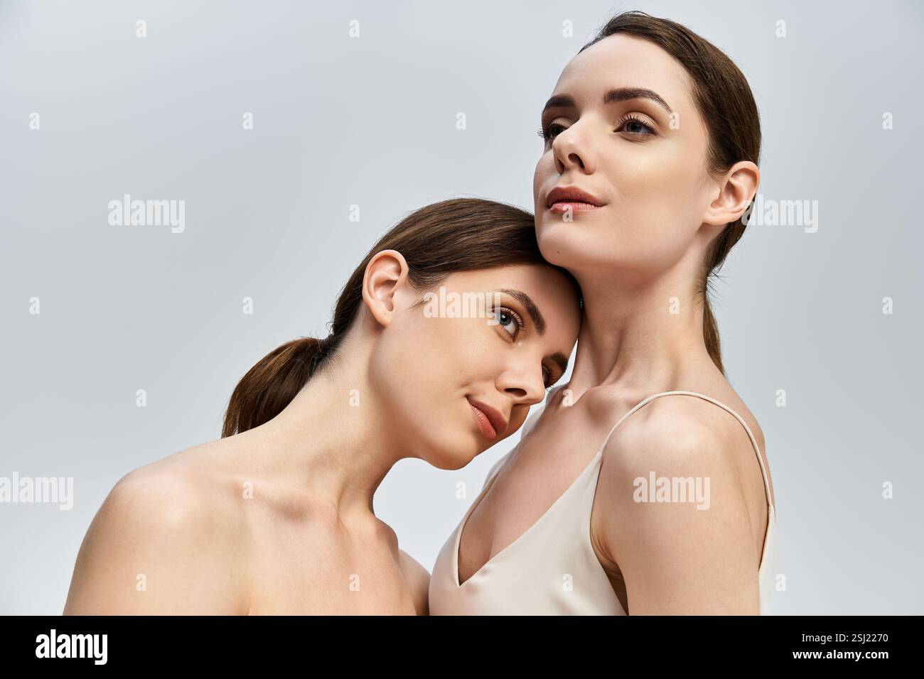 Two beautiful twin sisters elegantly pose together, radiating grace and ...