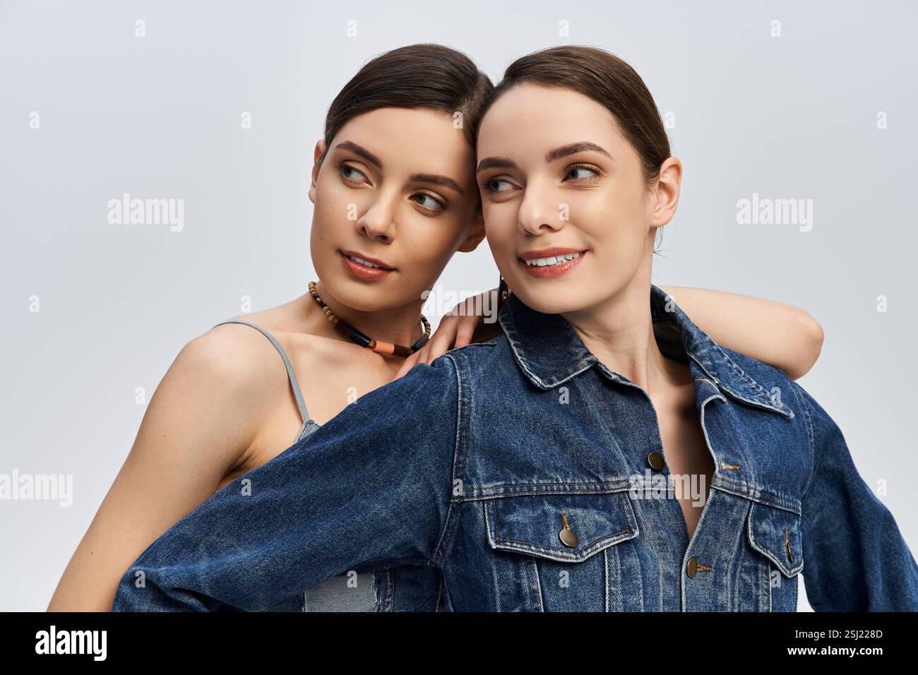 Two pretty sisters embrace each other, smiling and enjoying their time ...