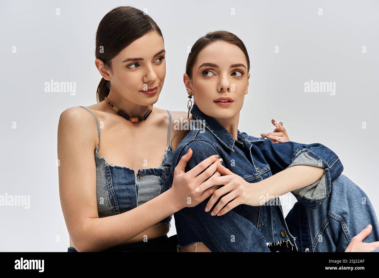 Two beautiful women, twins and sisters, pose gracefully together in a ...