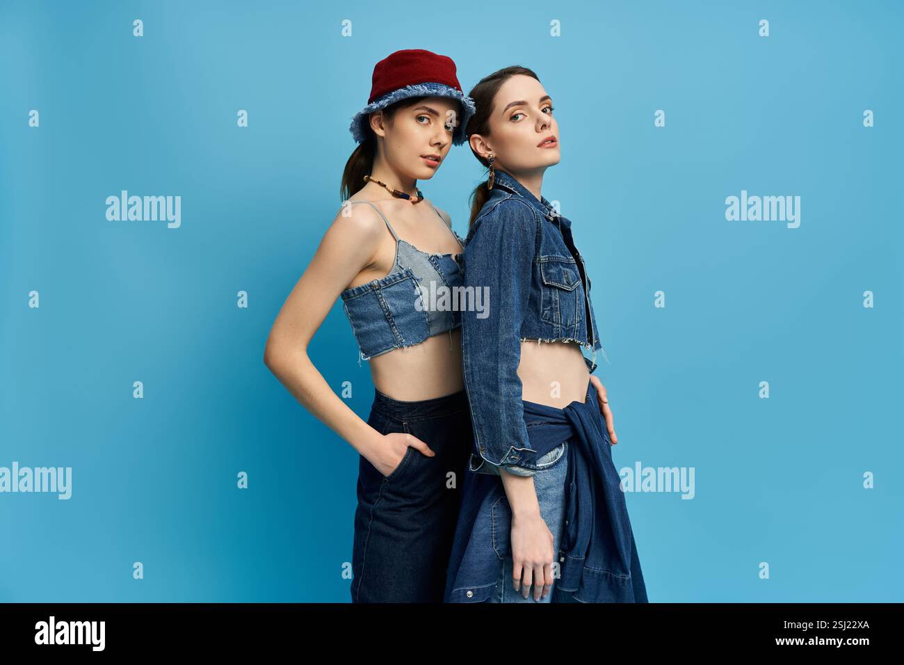 Two pretty women display stylish denim outfits while posing back to ...