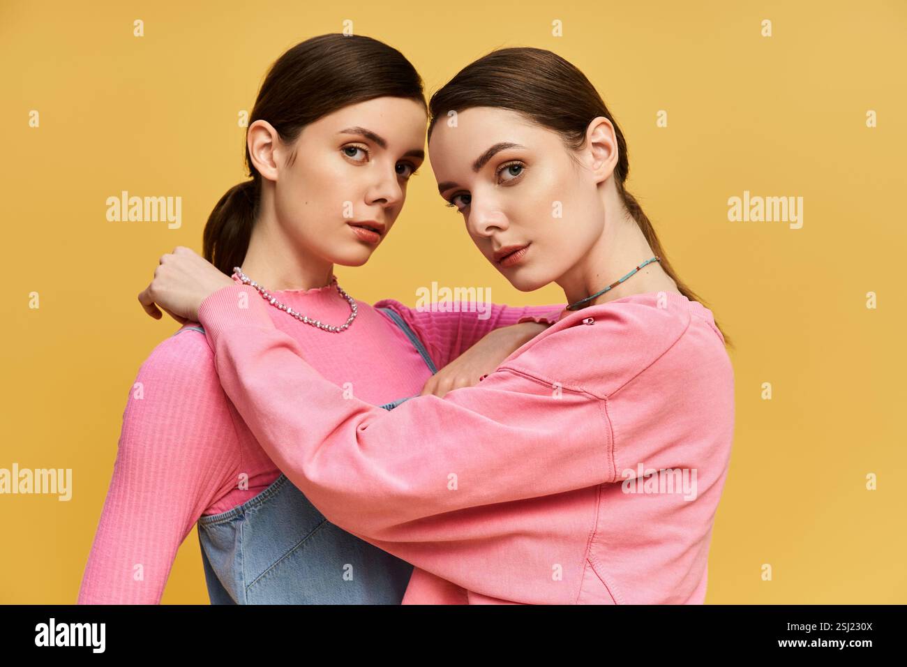 Two beautiful twin sisters pose together with confident expressions ...