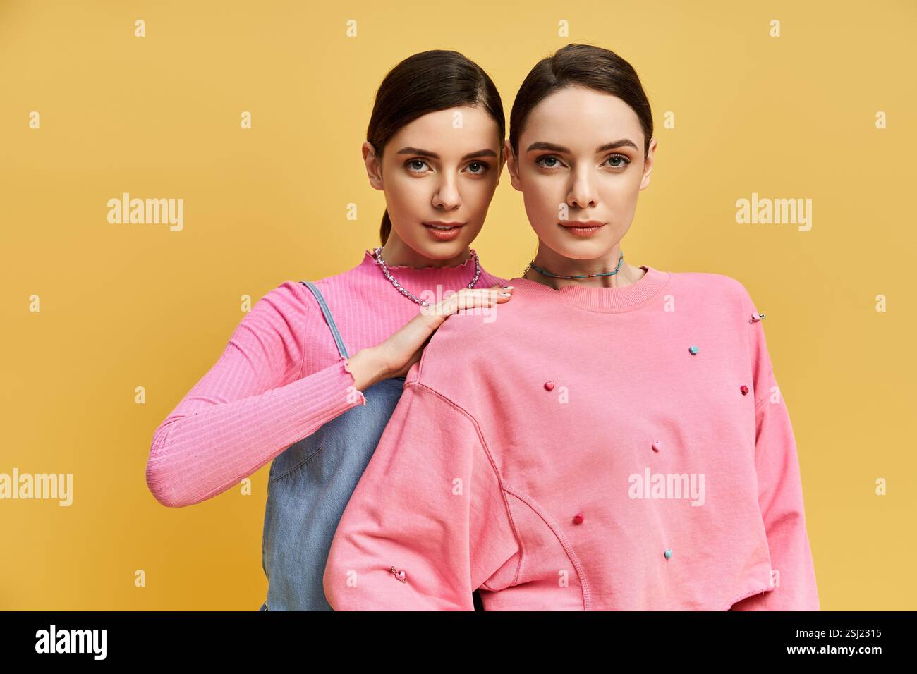 Twin sisters show off their unique styles against a bright yellow ...
