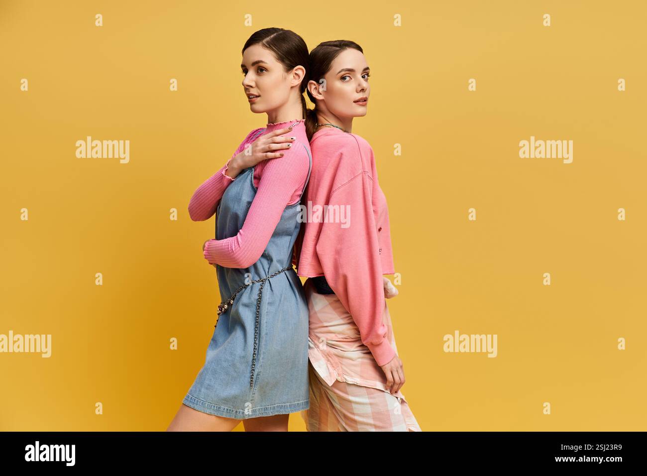 Two beautiful sisters stand confidently back to back, showcasing their ...
