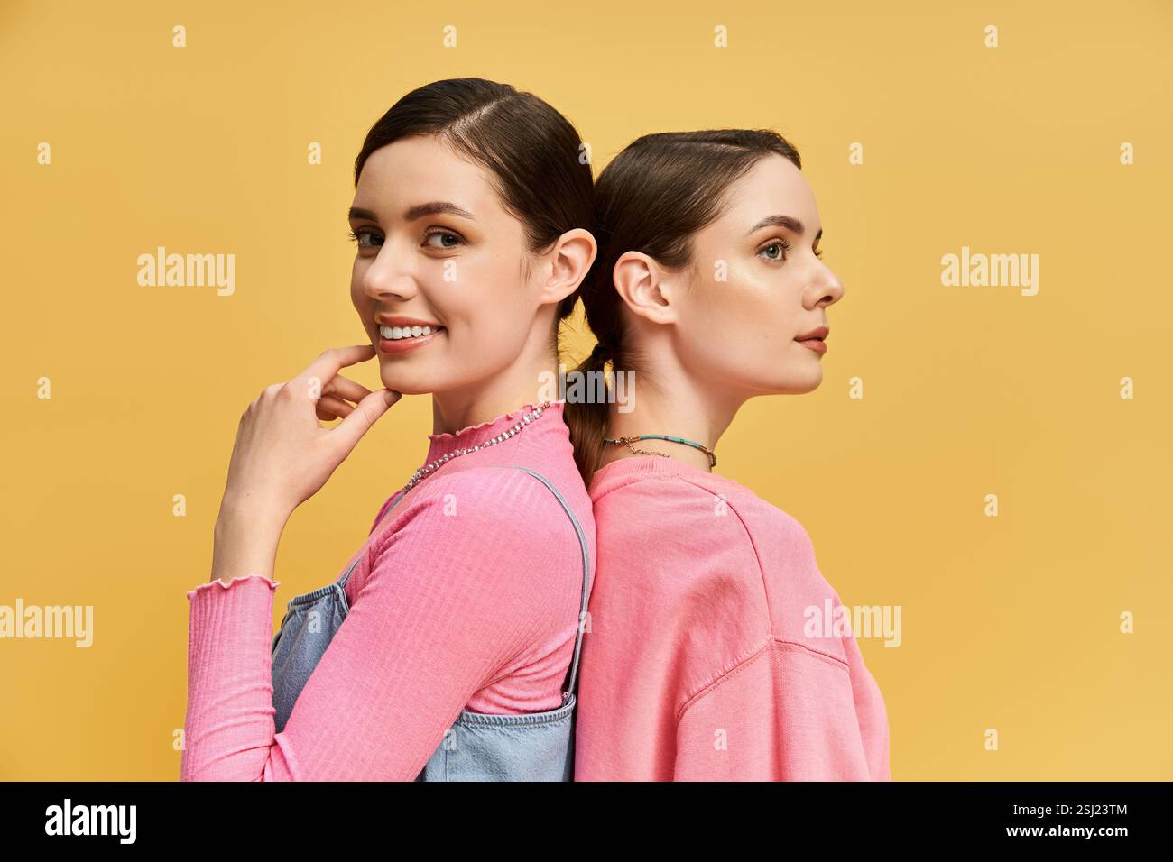 Beautiful sisters pose back to back, sharing joyful smiles in a ...