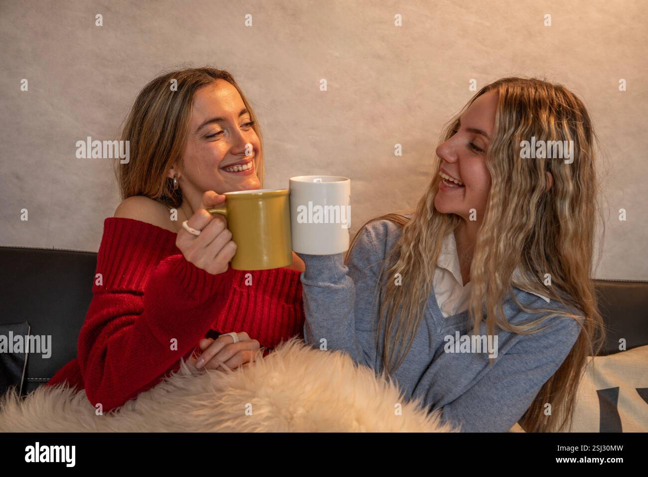 Two happy female friends are enjoying a cup of tea together on a ...
