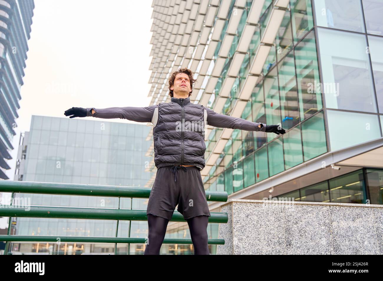 Male athlete performing warm-up exercises in a modern city setting ...