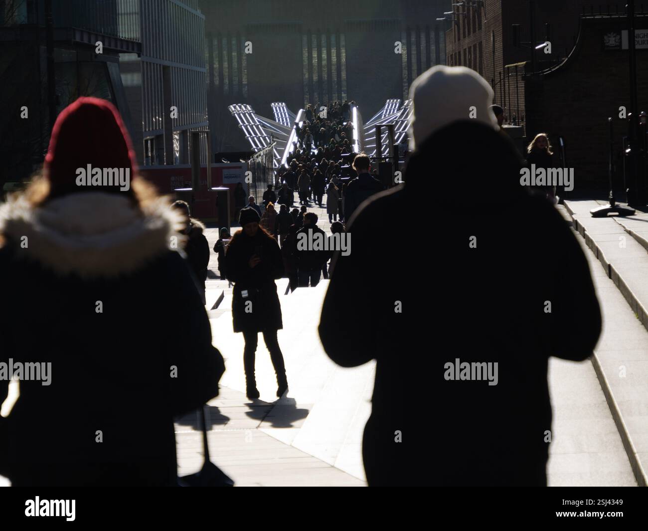 Busy crowds cross the iconic Millennium Bridge, a pedestrian pathway ...