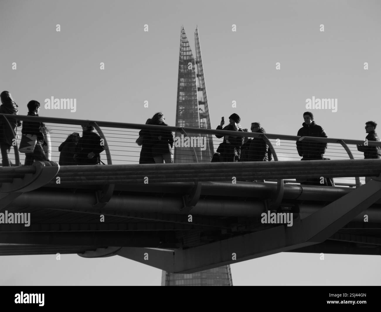 Busy crowds cross the iconic Millennium Bridge, a pedestrian pathway ...