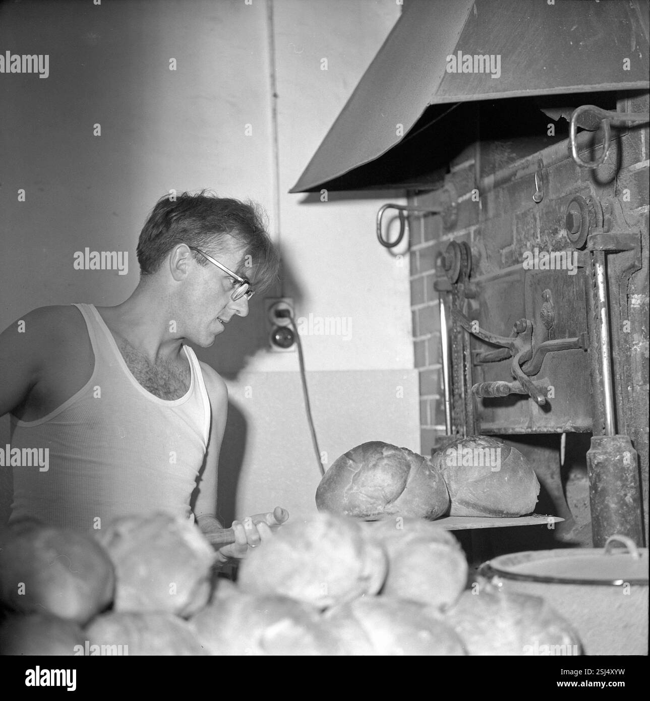 Bäcker entnimmt Brotlaibe aus dem Holzbackofen; 1965#Baker removing ...