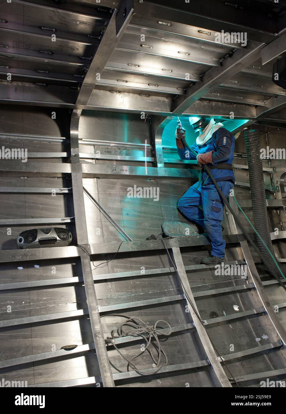 Welder at work welding aluminium. Shipbuilding Industry. Aluminium hull of a super sailing yacht ...
