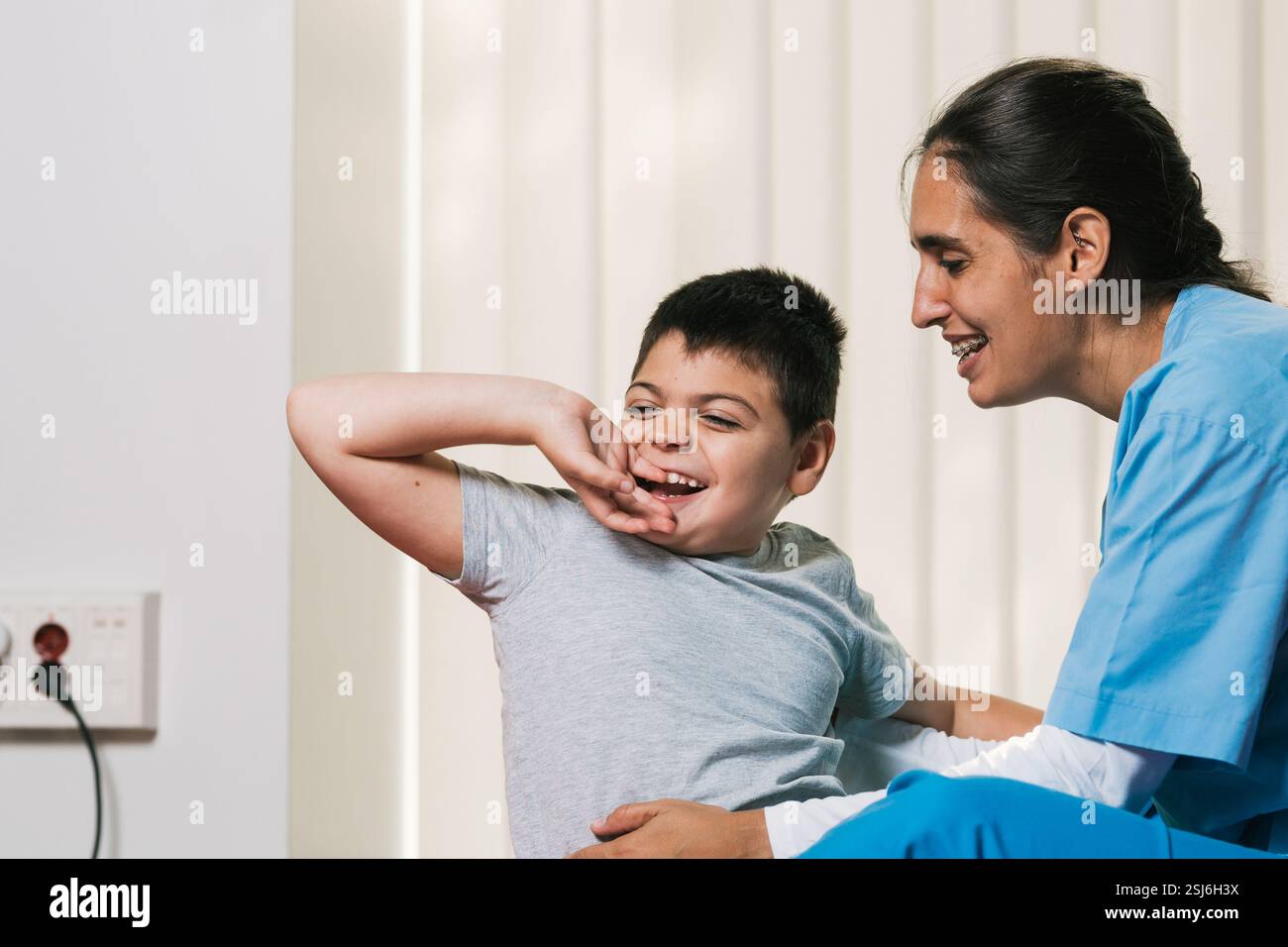 Physiotherapist assisting a child with disability with cerebral palsy ...